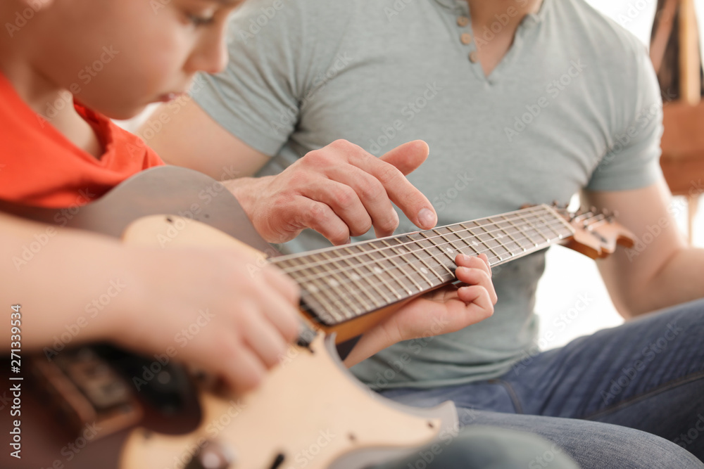 Little boy playing guitar with his teacher at music lesson, closeup ...