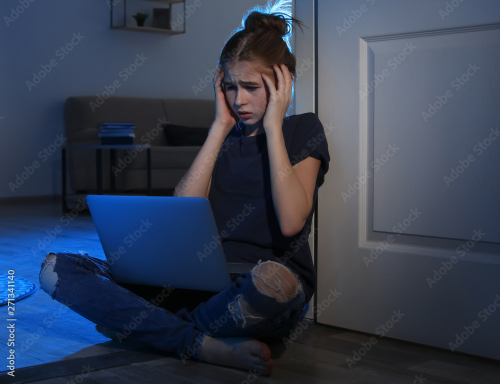 Terrified teenage girl with laptop on floor in dark room. Danger of ...