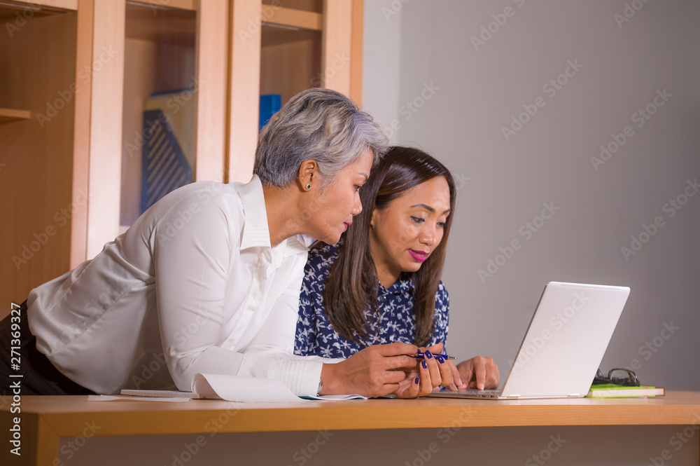 two women work colleagues or business partners working together reading ...