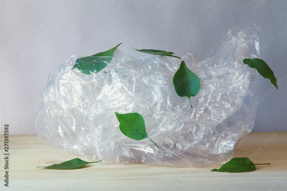 plastic warp with green leaves on wooden table, world environment day ...