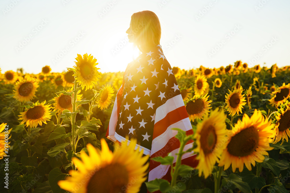 Beautiful girl with the American flag in a sunflower field. 4th of July ...