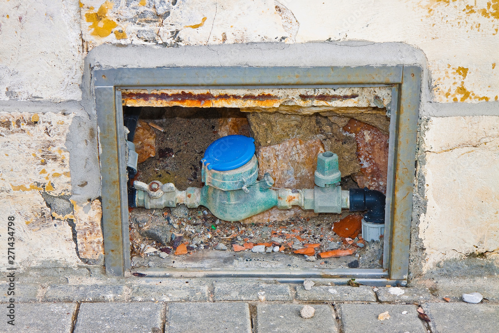 Old and rusty domestic water meter placed on the ground on a damaged ...