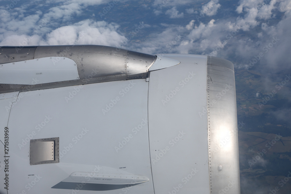 In-flight view on aircraft engine above dark ground and white clouds ...