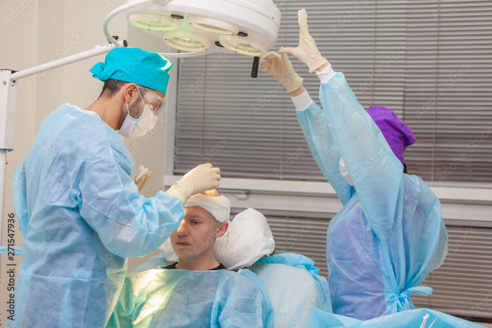 The surgeon directs the lamp light. Baldness treatment. Hair transplant ...