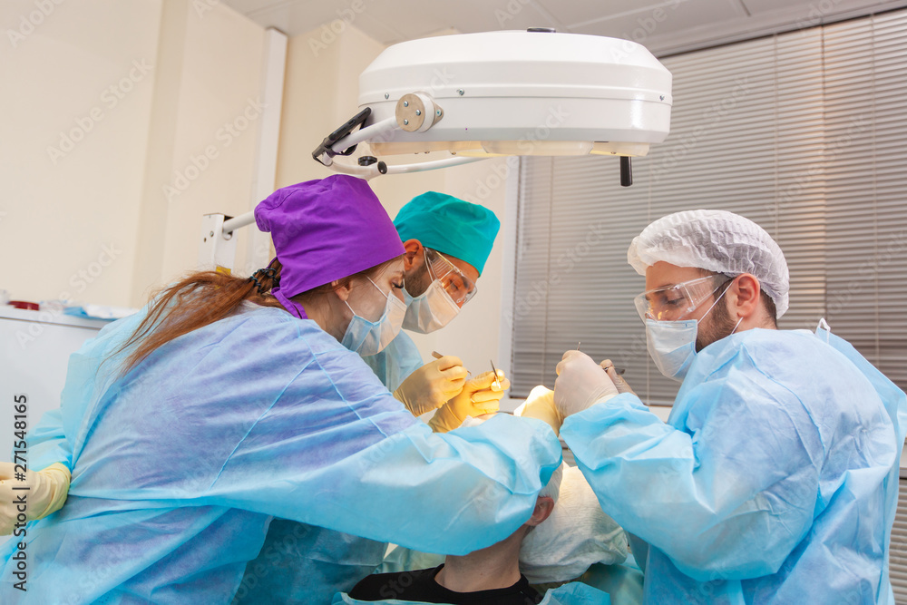 Baldness treatment. Hair transplant. Surgeons in the operating room ...