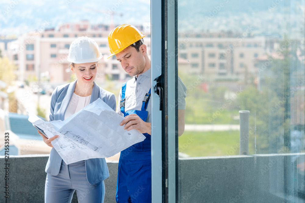 Principal and builder reading blueprints on construction site Stock ...