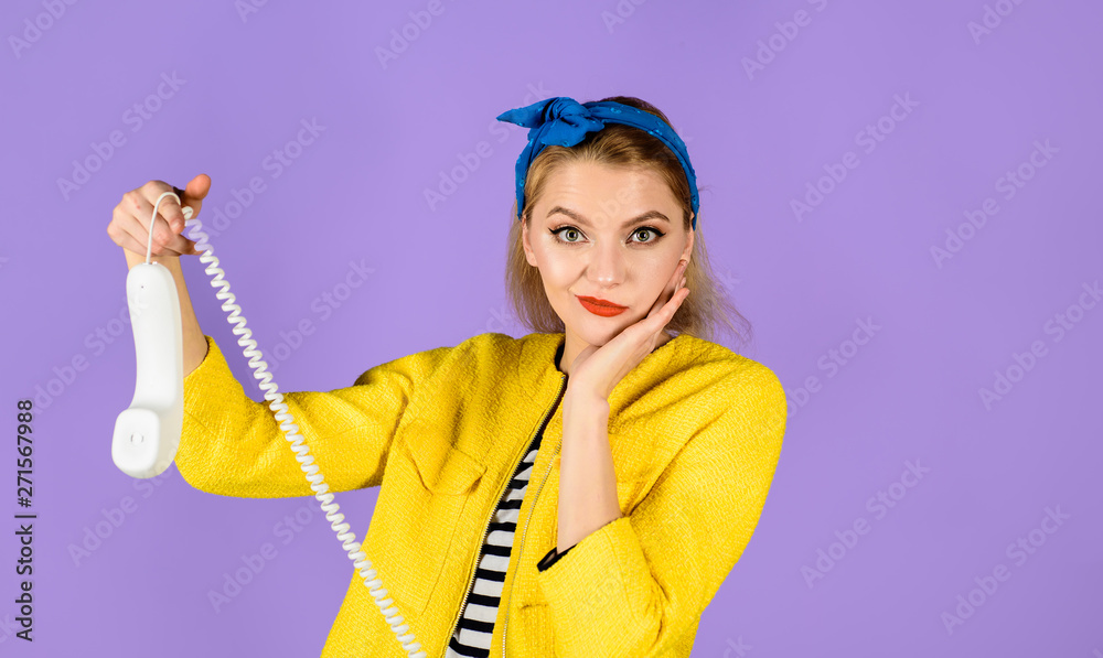 Worried woman holds wire phone handset. Surprised woman in headband ...