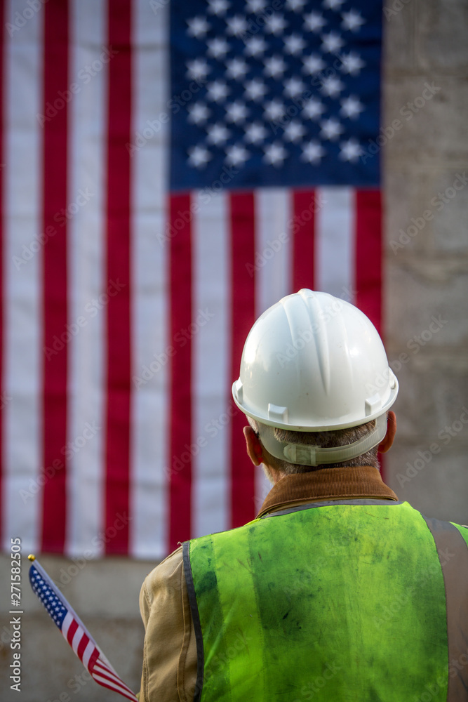 construction worker in hard hat on a concrete wall and american flag ...