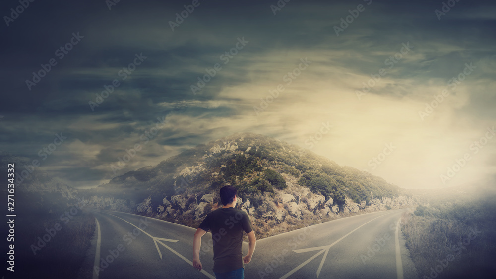 Rear view man walking in front of crossroad as road is split in two ...