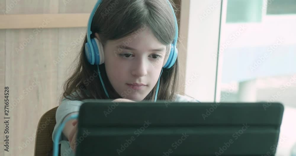 Young girl watching her tablet computer intensely smiles at the camera ...