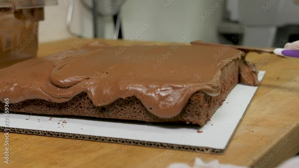 Baker Spreads Icing On Single Layer Chocolate Cake. A baker smooths the ...