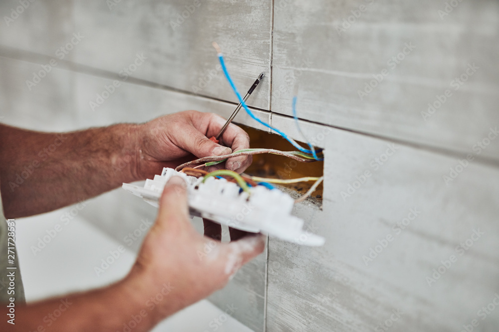 Electrician repairing / fixing wires in the wall. Stock Photo | Adobe Stock