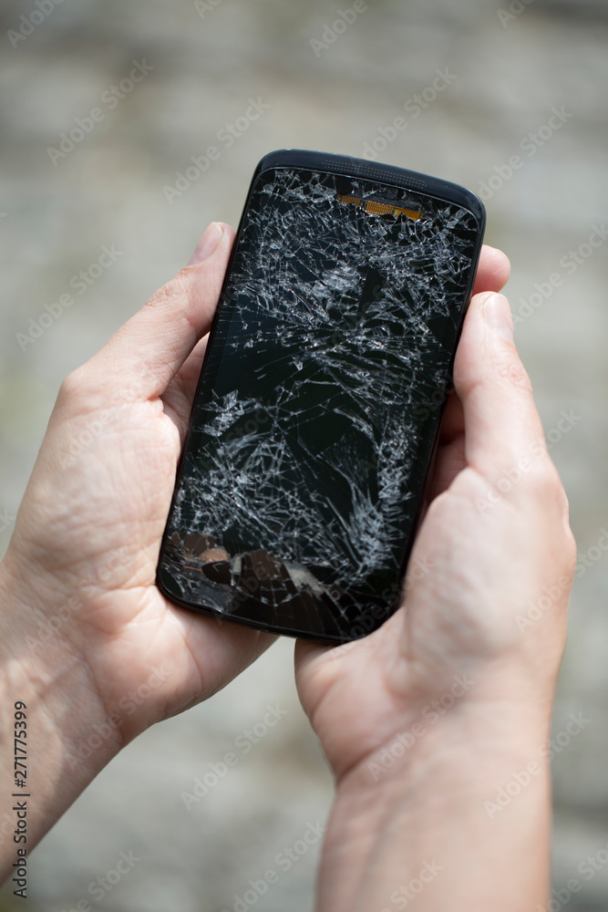 Broken glass screen smartphone in hand.Hand holding mobile phone with ...