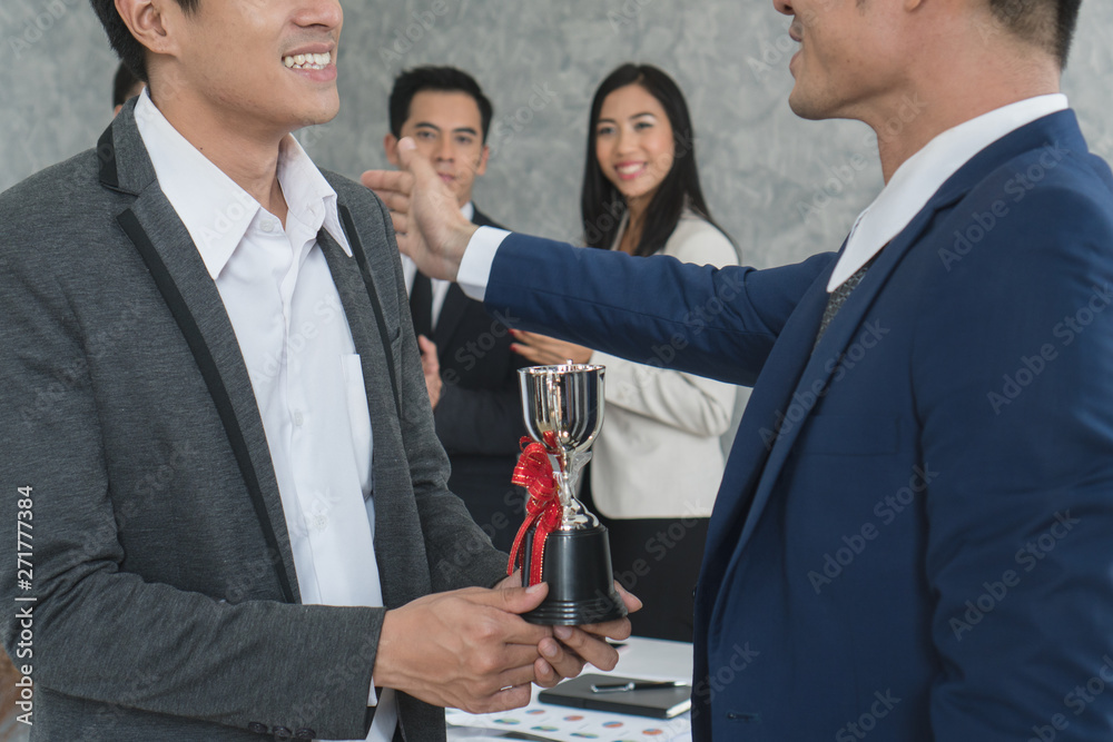Worker holding trophy prize for best employees of the month in his hand ...