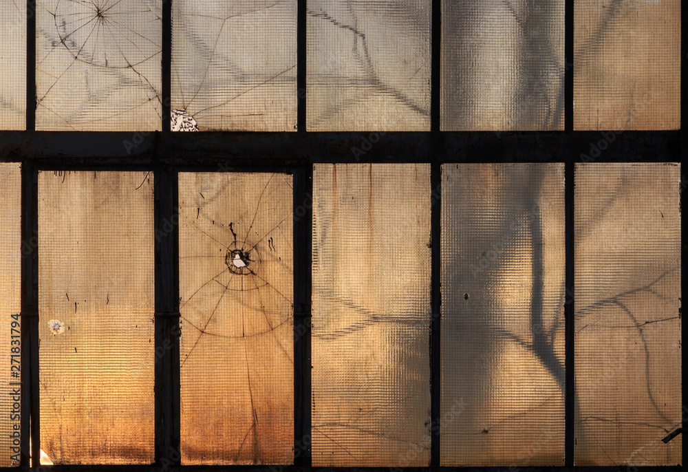 Cracked armed and stained glass panes with a few holes, at sunset ...