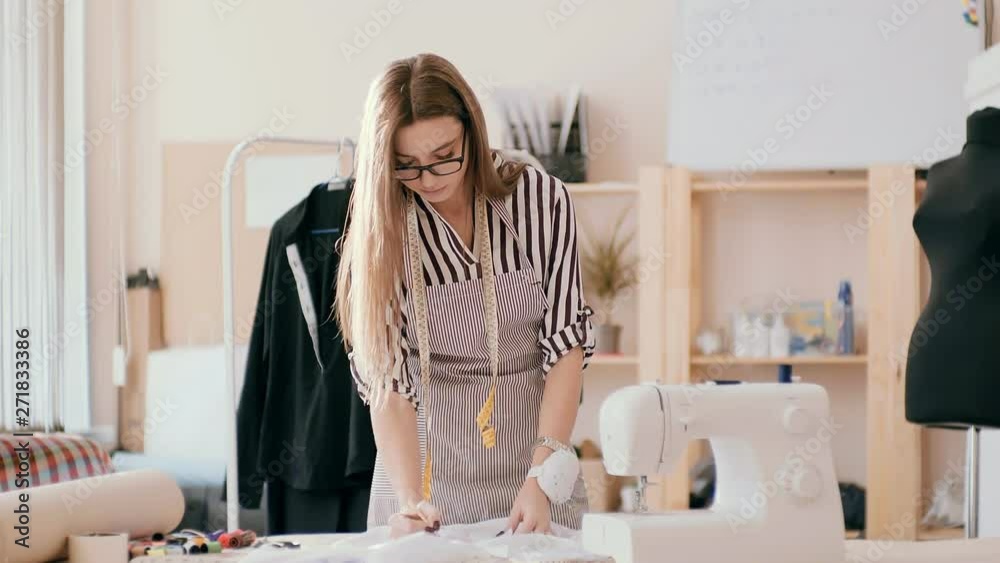 seamstress Caucasian appearance, carefully making marks with a pencil ...