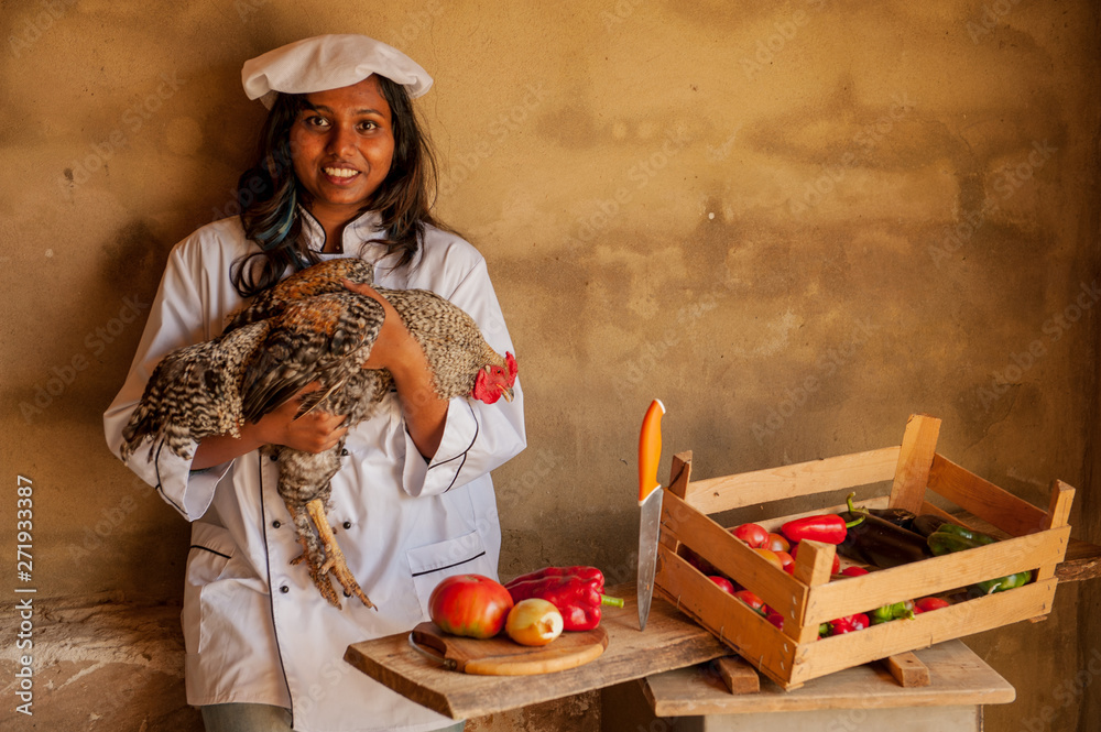 Attractive Indian woman cook posing in kitchen with chicken in her ...