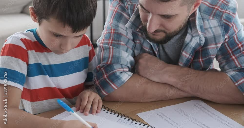 Father guiding his son doing homework at home Stock Video | Adobe Stock