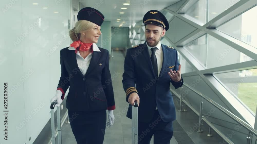 Handsome male pilot and attractive female flight attendant are walking ...