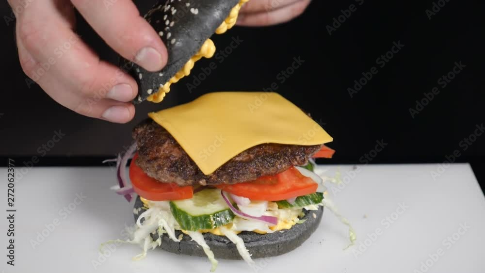 Slow motion food cooking. Hands preparing a hamburger. Close up view of ...