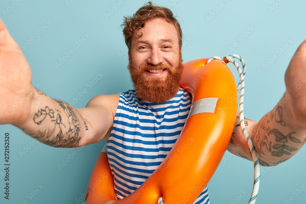 Joyful redhead man being on holiday at sea, makes selfie, poses against ...