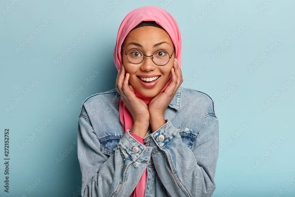 Beautiful happy Arabian female touches cheeks gently, has charming ...