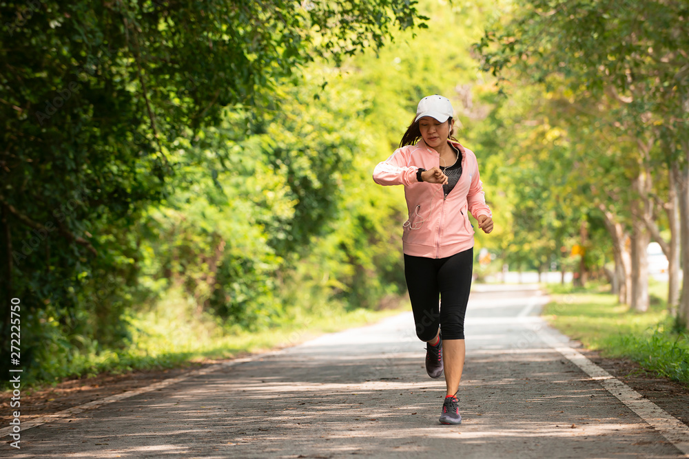 Asia woman runner running while checking heart rate at park, female in ...
