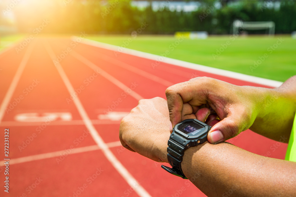 Athlete checking his watch on running track Stock Photo | Adobe Stock