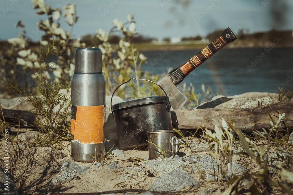 Thermos, pot, mug, hatchet stuck in a wooden log - a set of hiking ...