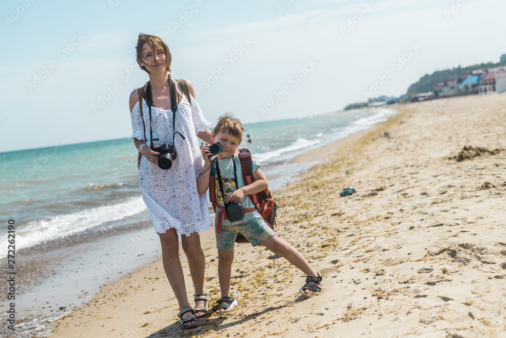 Mom and son with cameras on the beach, ocean. Joint occupation of ...