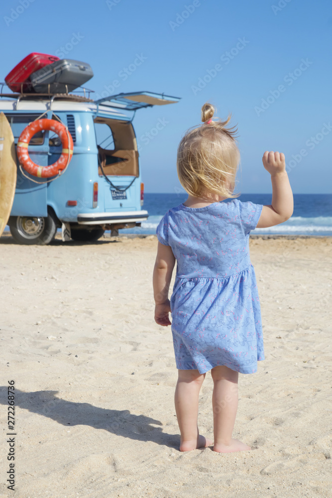 Foto de Back view of toddler girl in a blue dress waving goodbye at the ...