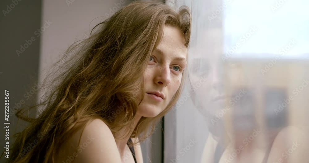 Portrait of a pretty girl model posing at a large panoramic window ...