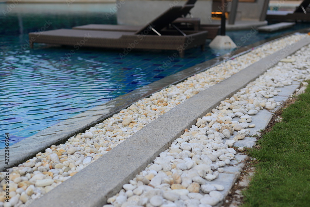 swimming pool grating covered with round white river pebble. drainage ...