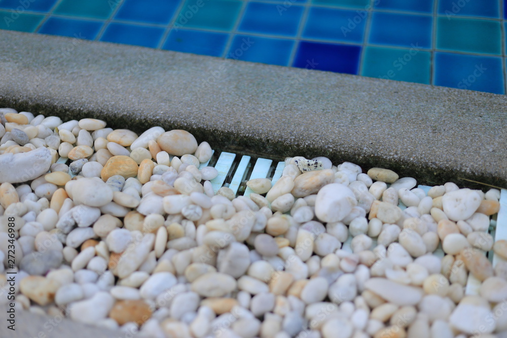 swimming pool drainage system grating covered with round white river ...