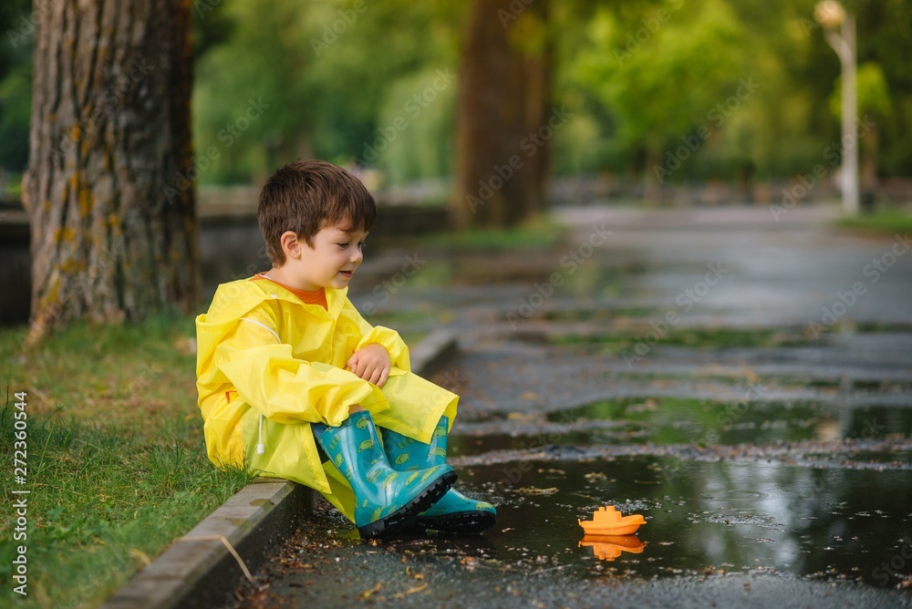Child playing with toy boat in puddle. Kid play outdoor by rain. Fall ...