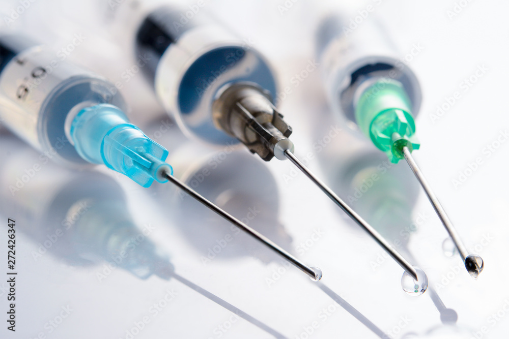 Three used syringes with medicinal solution, on light green background ...