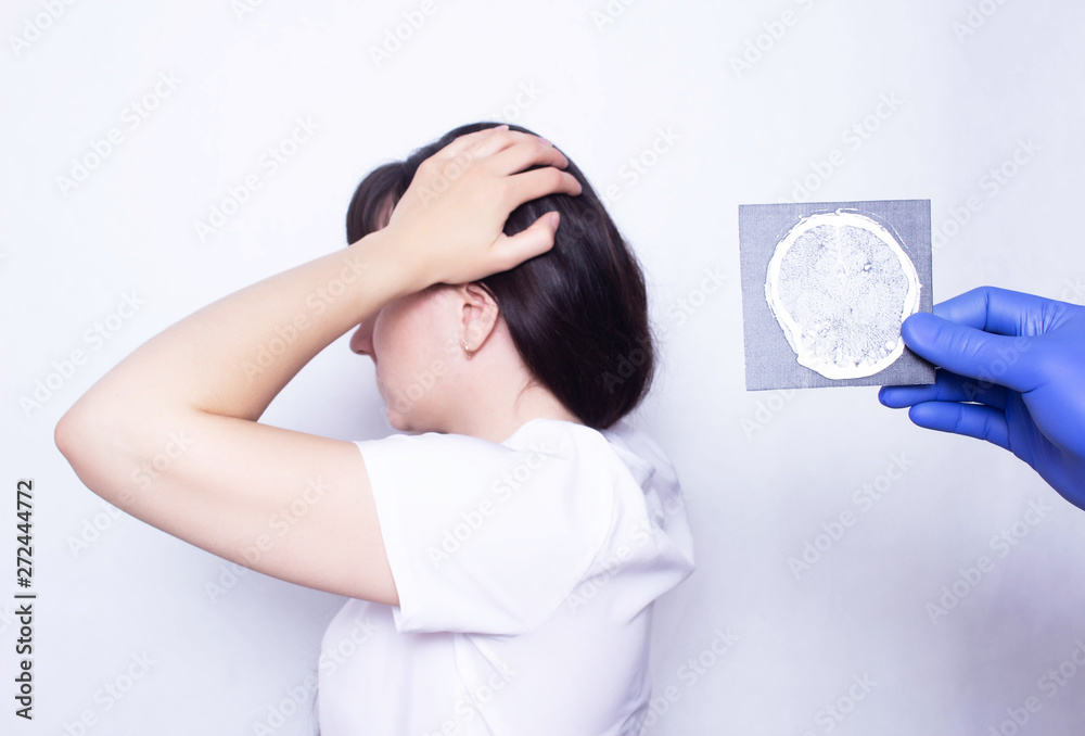 A doctor holds an x-ray of a patient caucasian girl with a headache and ...