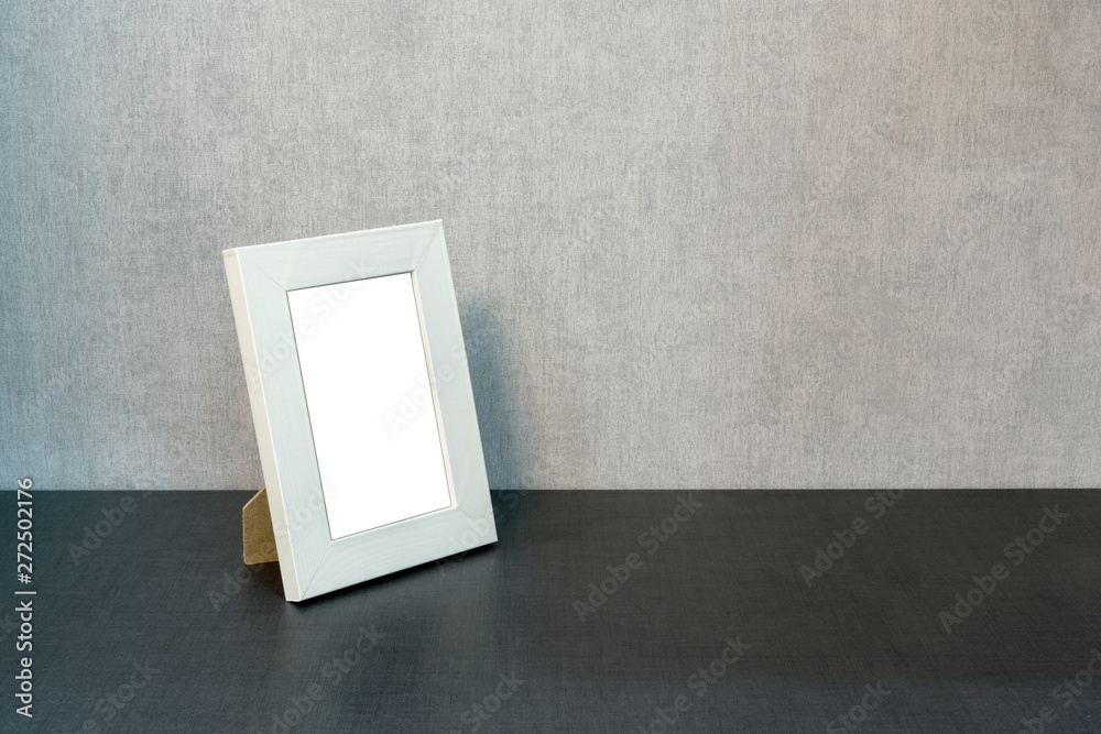 one small empty white frame for a picture and a photo on the shelf at ...