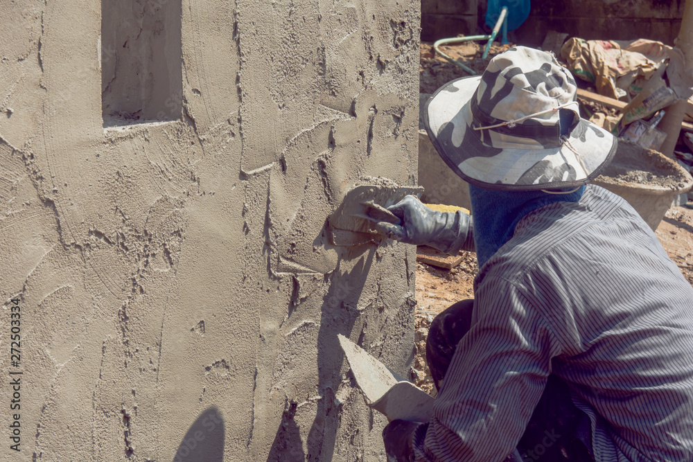 Construction workers plastering building wall using cement plaster ...