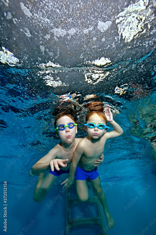 Sporty little boys, two, brothers. Hugging and swimming in the pool, on ...