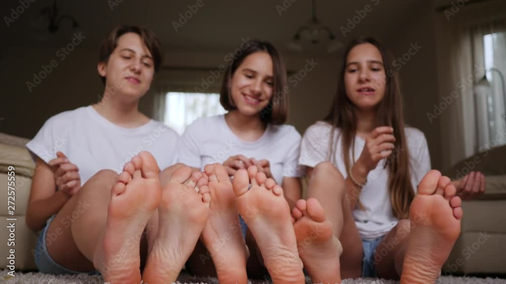 Teenager girls triplet sisters at home sit on carpet and interlace ...