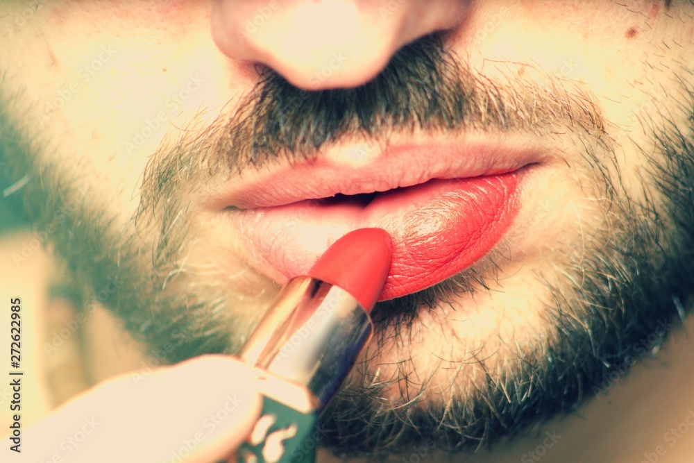 A young man depicts his lips with red lipstick.The man looks like a ...