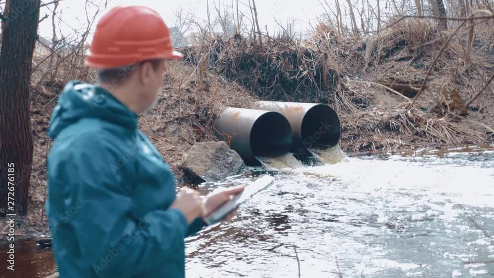 Environmental pollution. A man in a helmet and respirator with a tablet ...