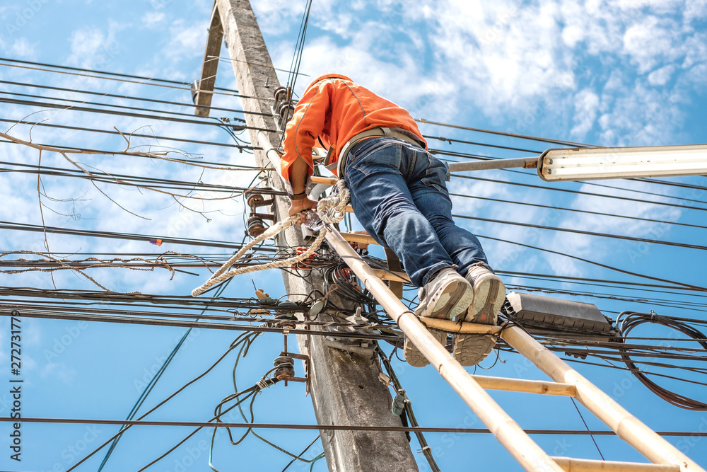 Electrical linemam worker climb a bamboo ladder to repair wire. A ...