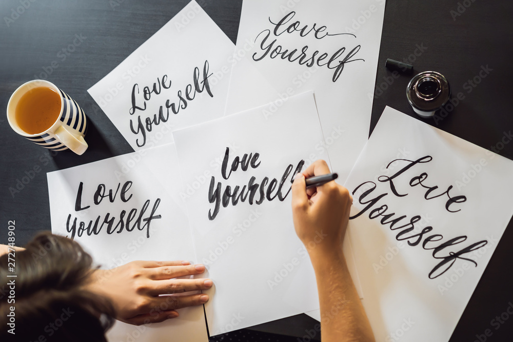 Love yourself. Calligrapher Young Woman writes phrase on white paper ...