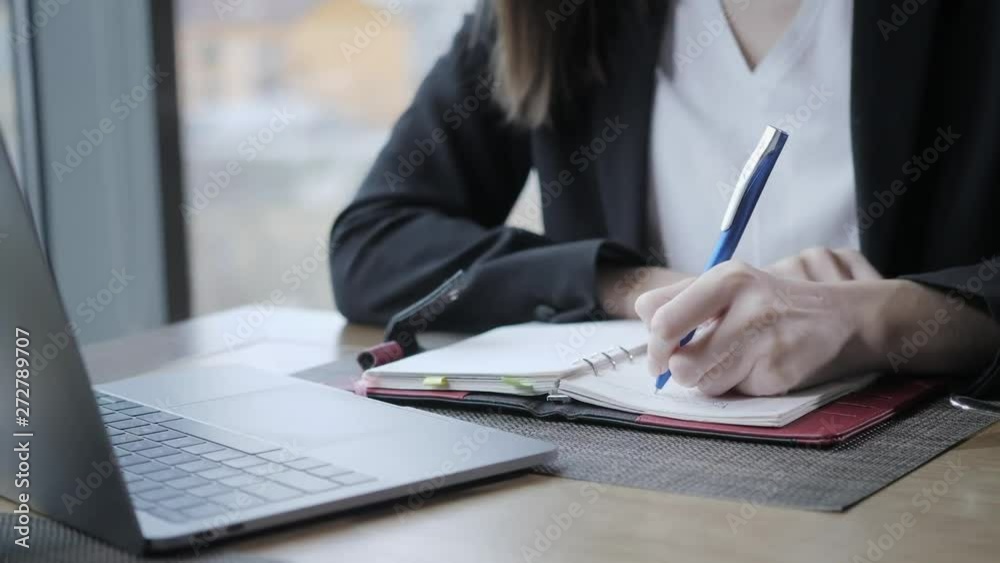 Close-up hand of a woman making notes in a notebook. Young ...