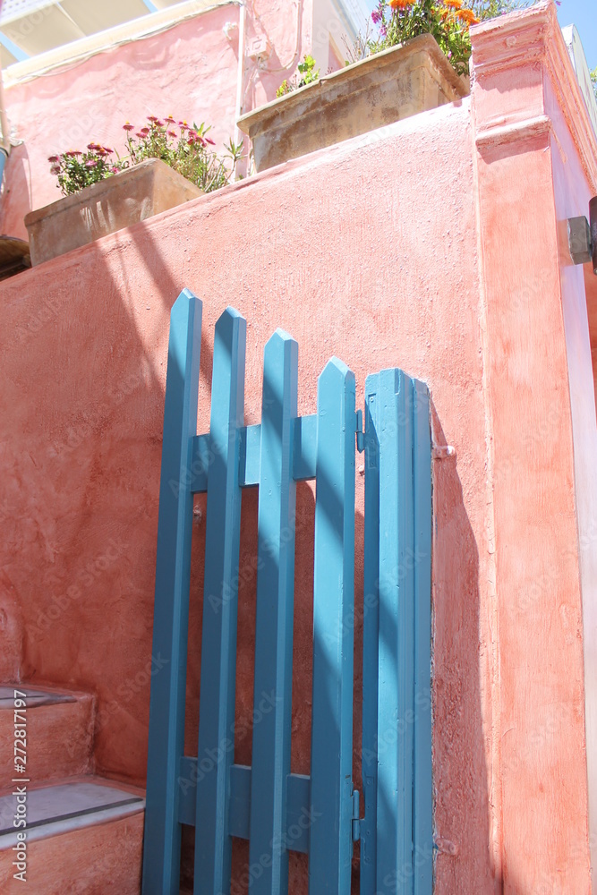 Blue opened gate and pink wall. Mediterranean village with stone houses ...