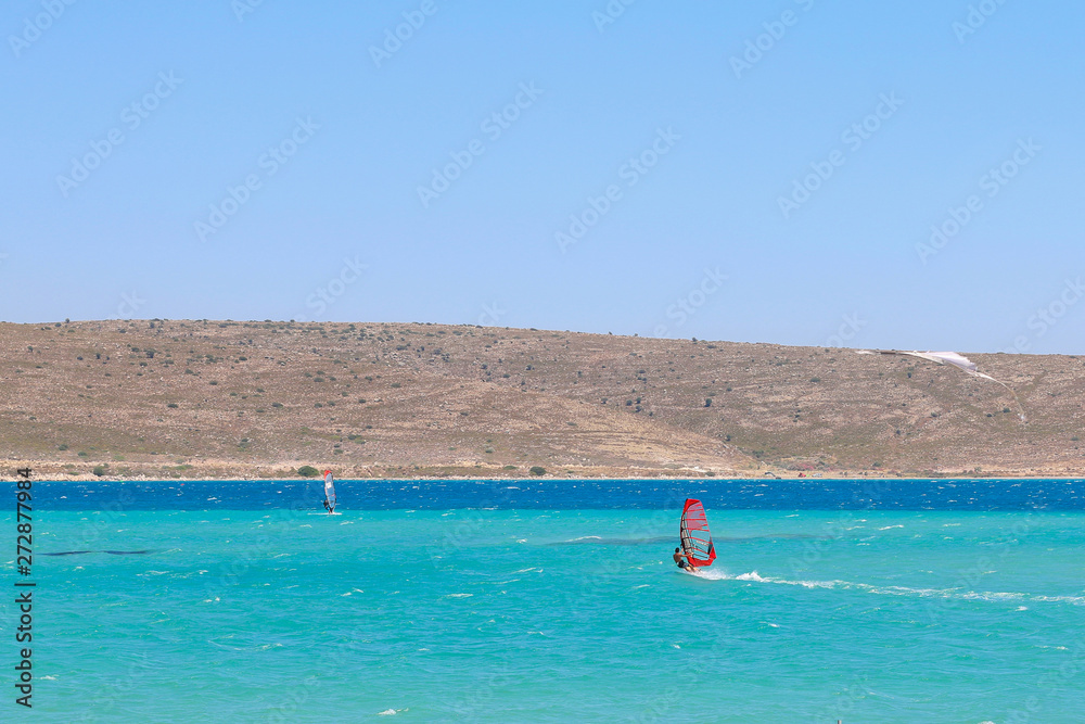 Foto de Windsurfer sails on turquoise waters of Alacati Windsurf Bay of ...