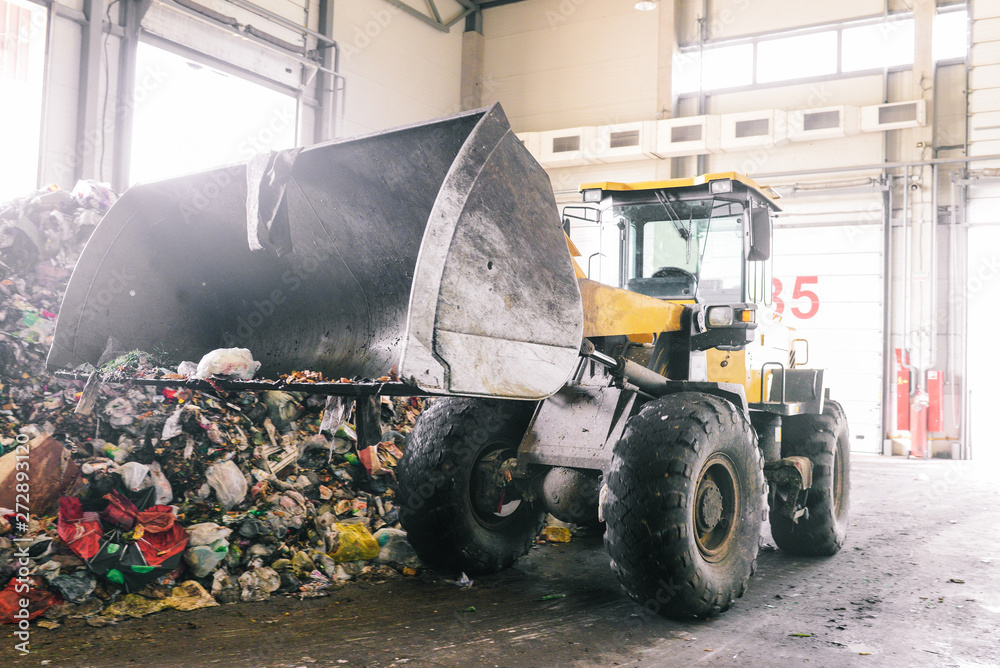 Hangar automated plant for sorting household waste. An excavator with a ...