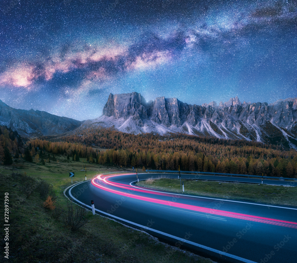 Milky Way over mountain road. Blurred car headlights on winding road in ...